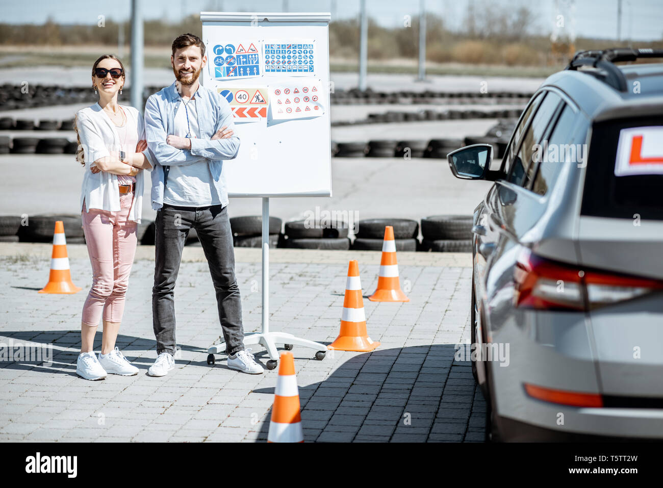 Portrait of an instructor and female student standing with road signs ...