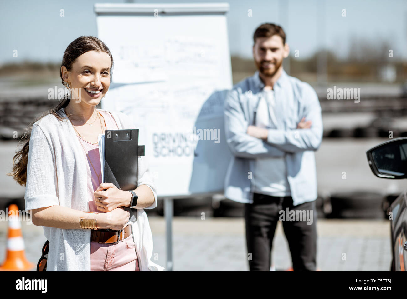 Portrait of a young female student and driver instructor standing on ...