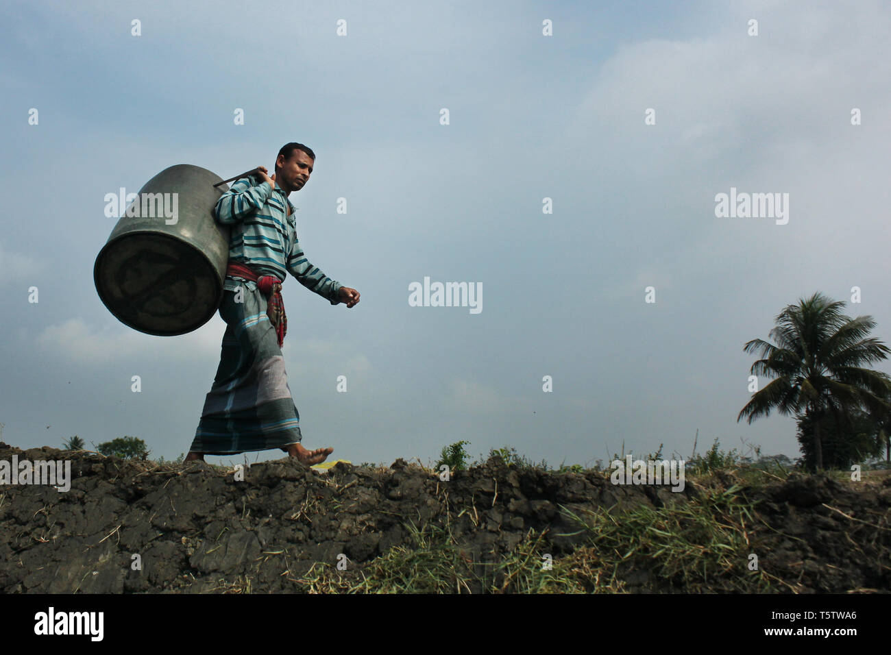A fisherman walks home along the banks of the Rupsha River in Khulna ...