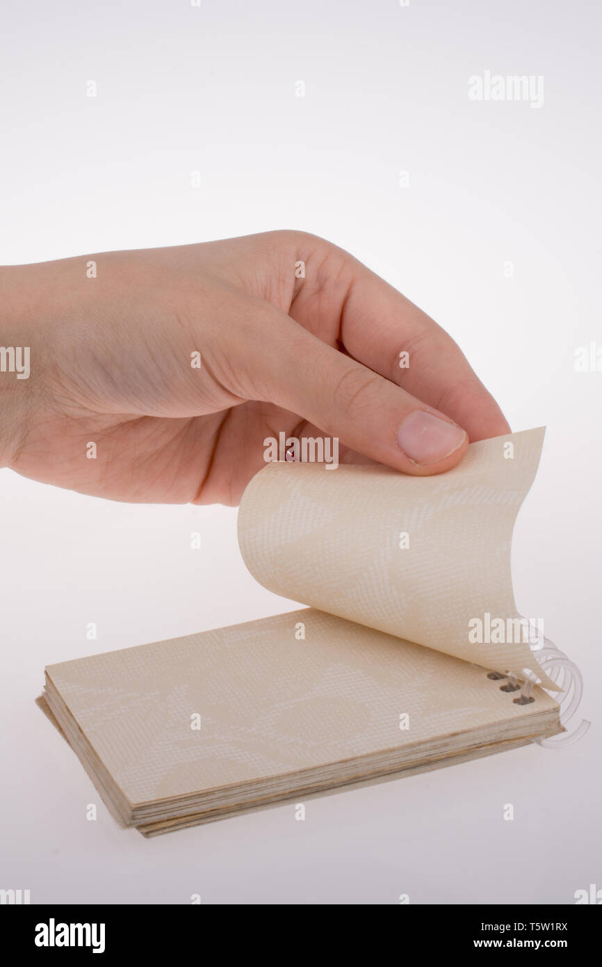 Hand holding a spiral notebook on a white background Stock Photo - Alamy