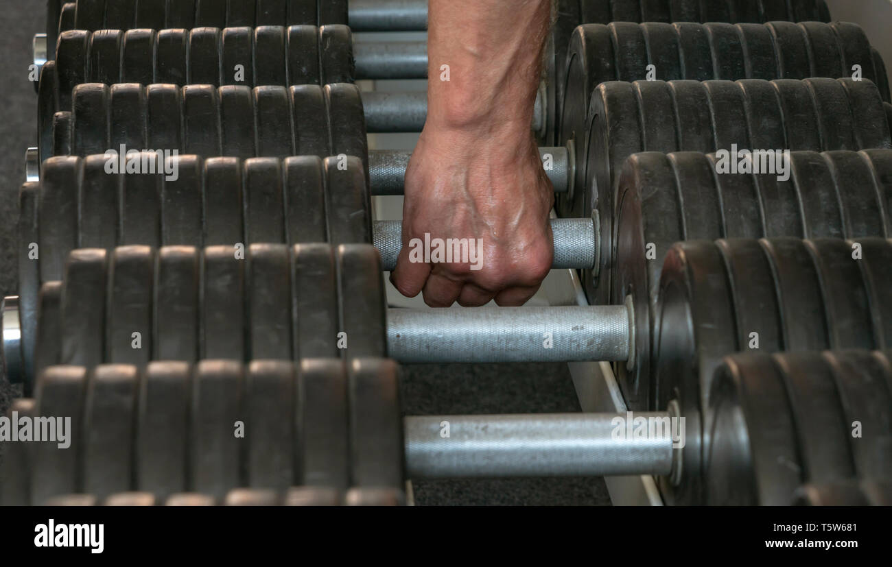 The hand of the athlete takes the barbell from the stand in the sports ...