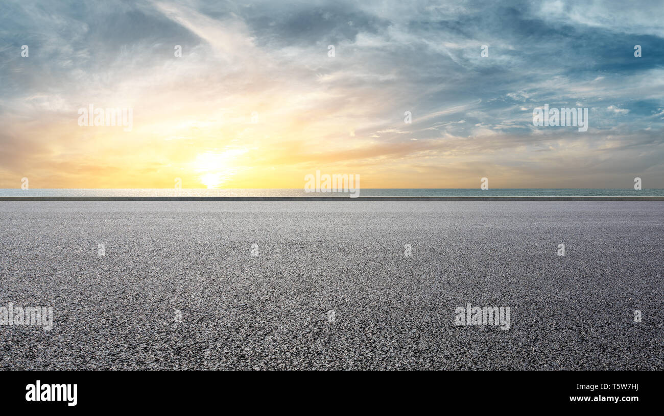 Empty asphalt road and sea with beautiful clouds at sunset Stock Photo ...