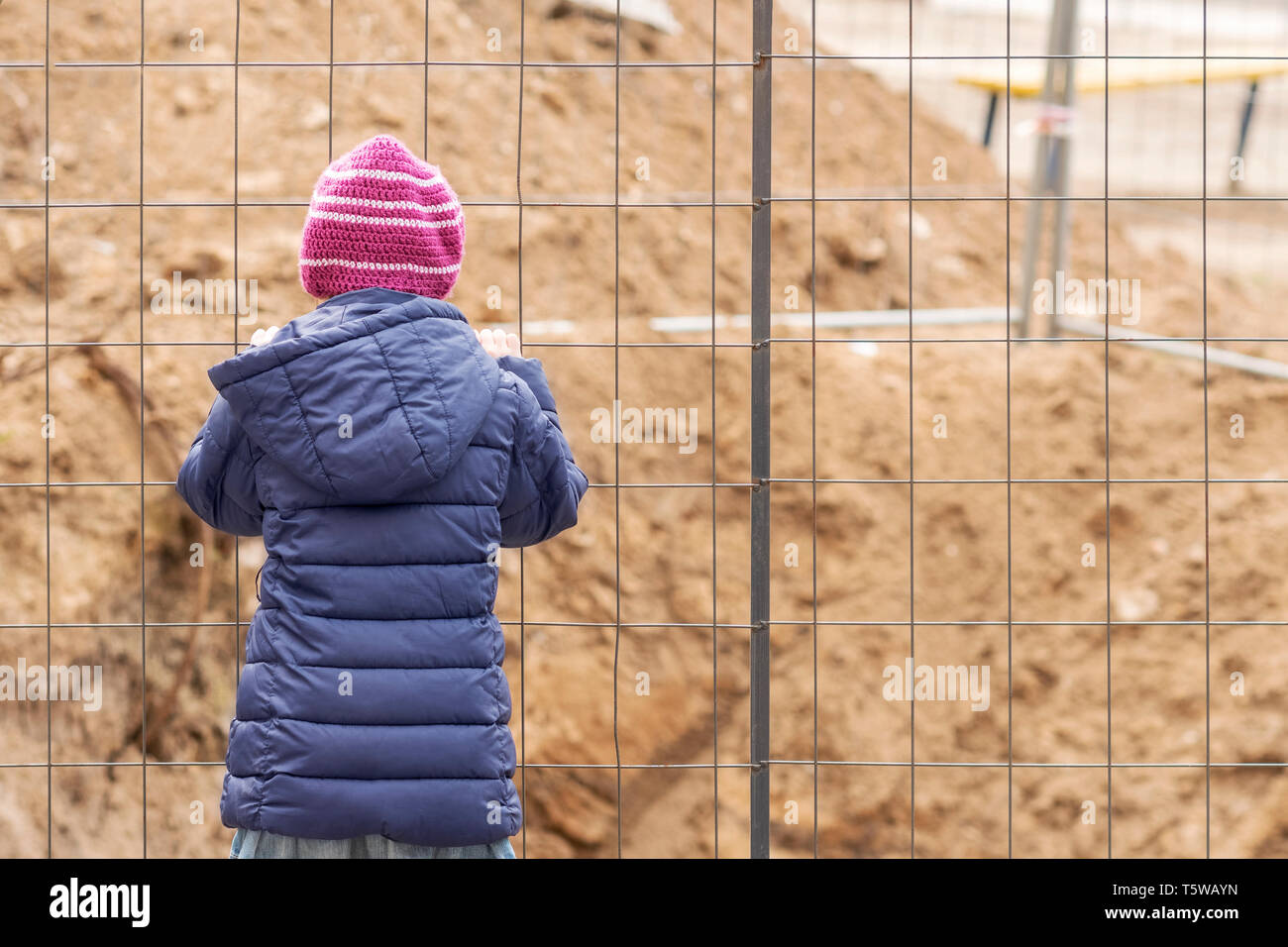 small child behind a metal fence with his back to the camera Stock ...