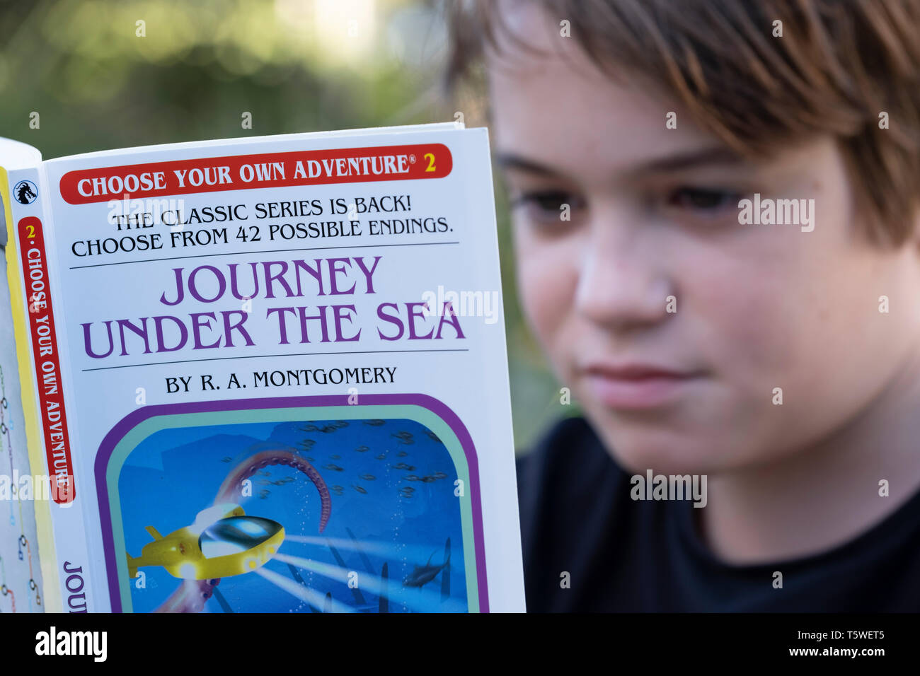 Choose Your Own Adventure Book with boy reading and reacting Stock ...