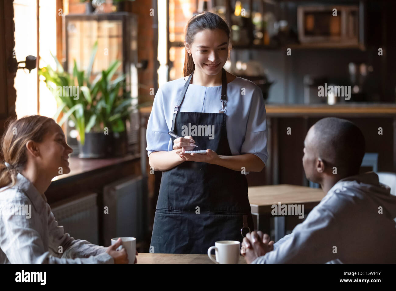 Waitress welcoming restaurant guests take order writing on notepad ...