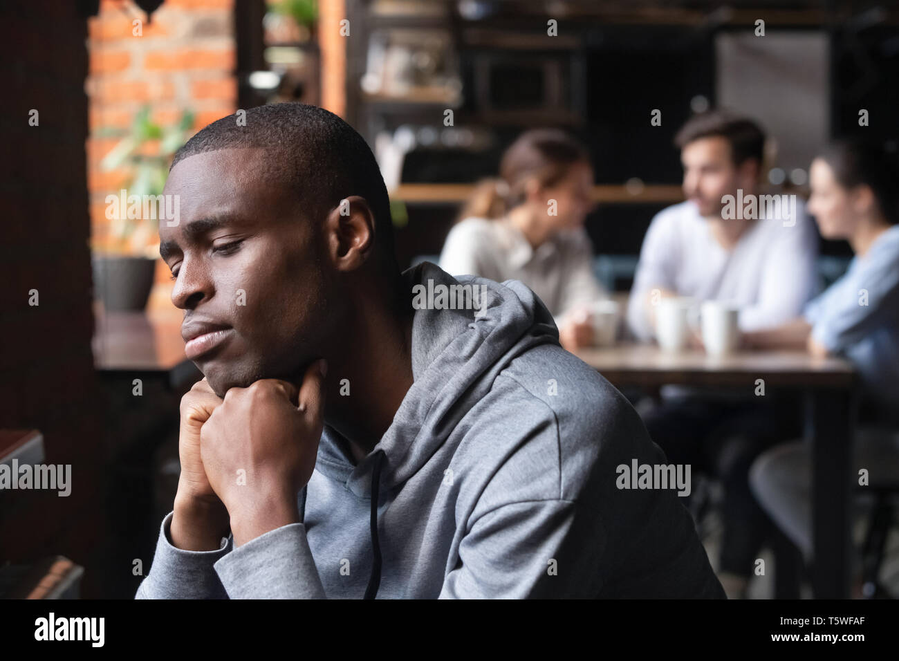 Sad african guy feel lonely sitting alone in cafe Stock Photo - Alamy