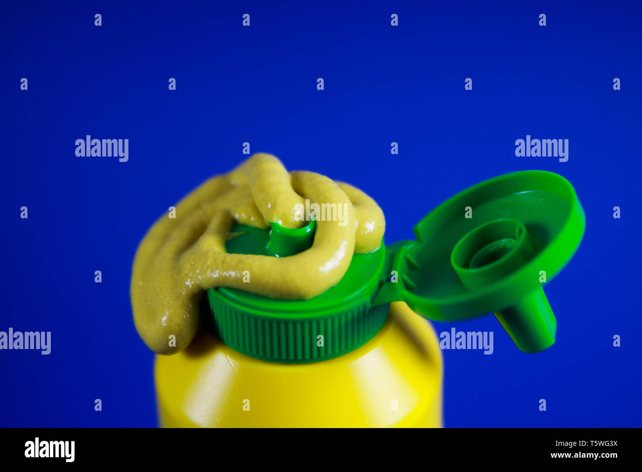 Close up of paste of mustard squeezed out a plastic bottle with blue ...
