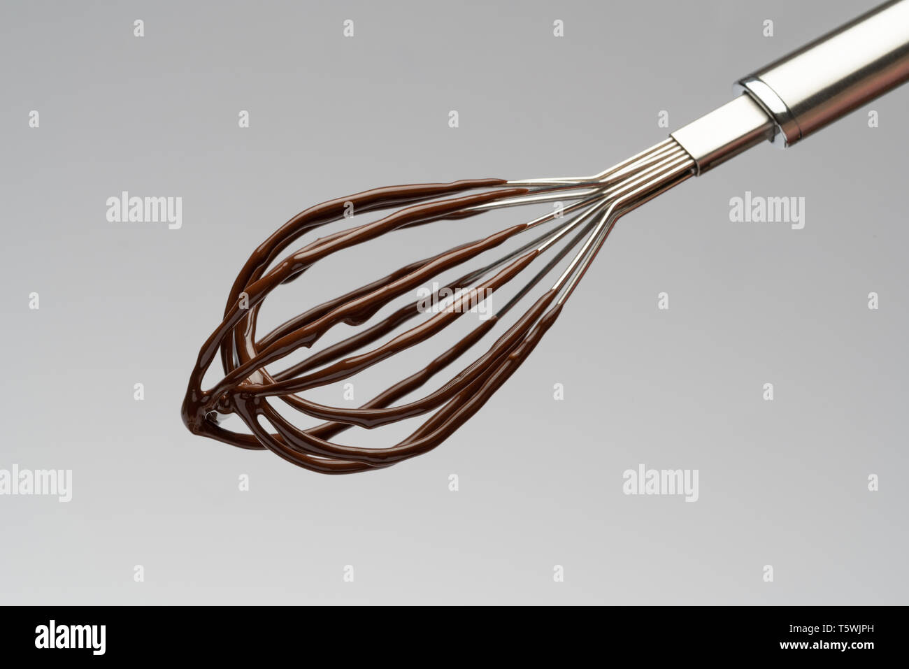 Whisk with liquid melted chocolate on light grey background Stock Photo ...