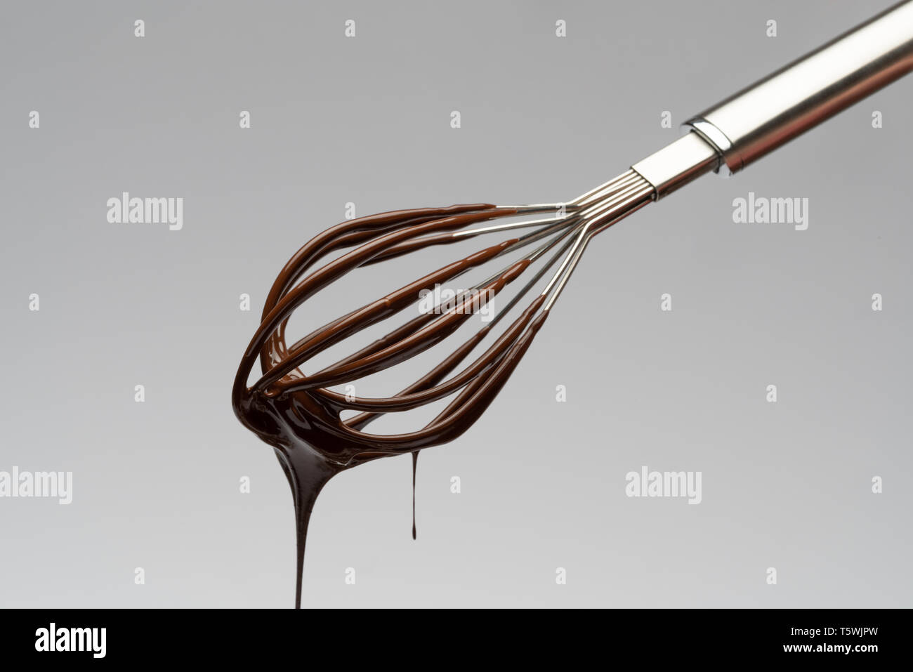 Whisk with liquid melted chocolate on light grey background Stock Photo ...