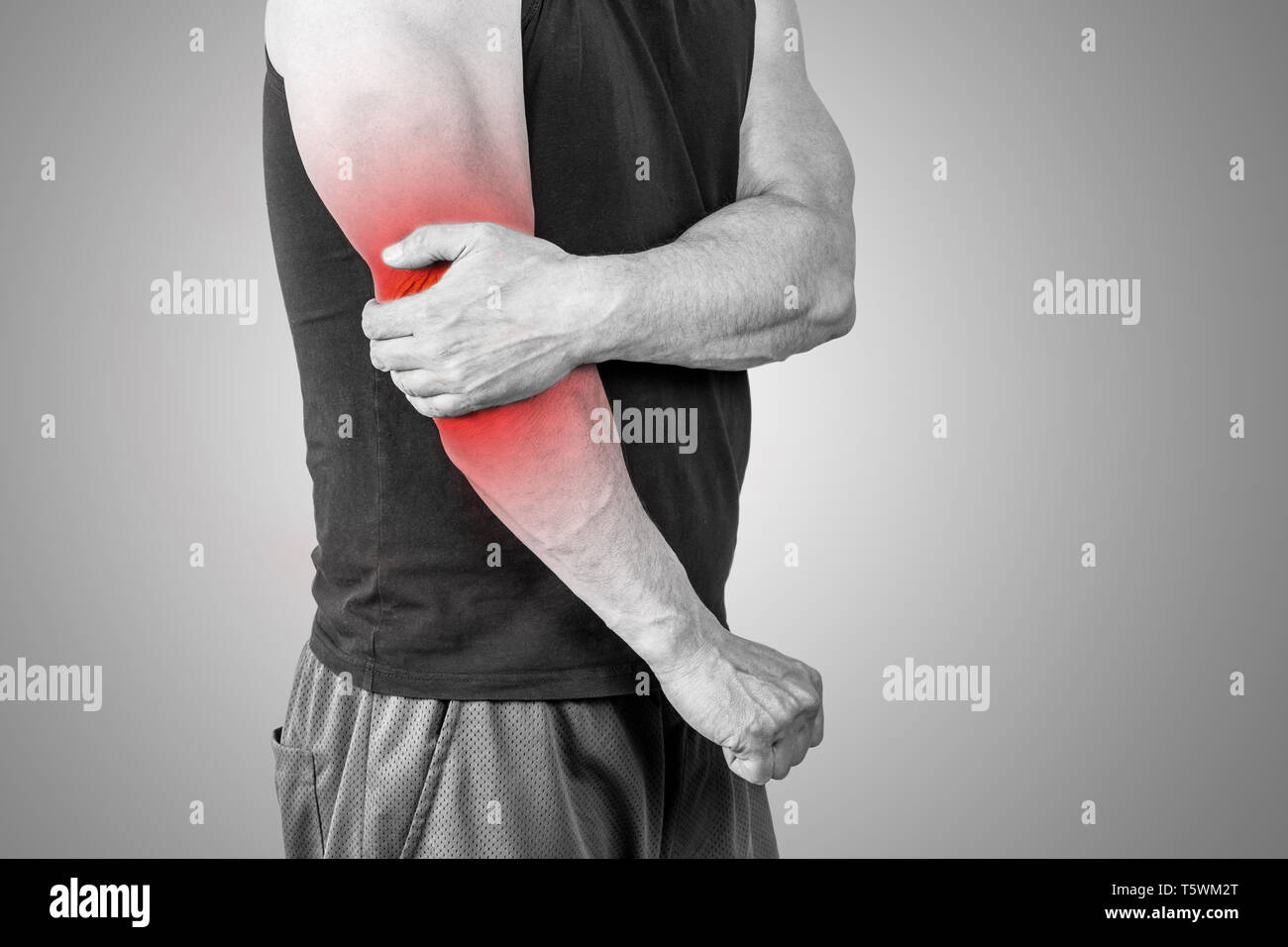Muscle man holds his injured elbow. Red color is pain Stock Photo - Alamy