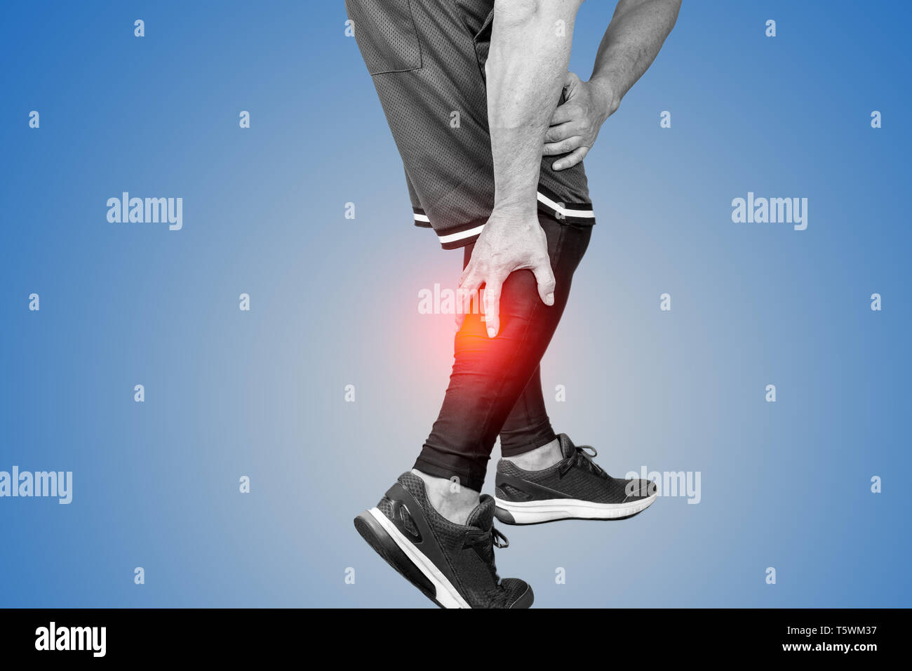 Muscle man holds his injured calf on blue background. Red color is pain ...