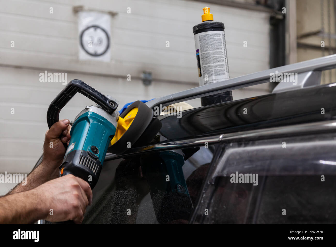 Close-up view on the hands of a man worker who holds a tool polisher ...