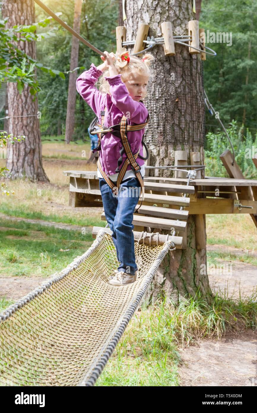 Child girl in adventure climbing high wire park, active lifestyle of ...