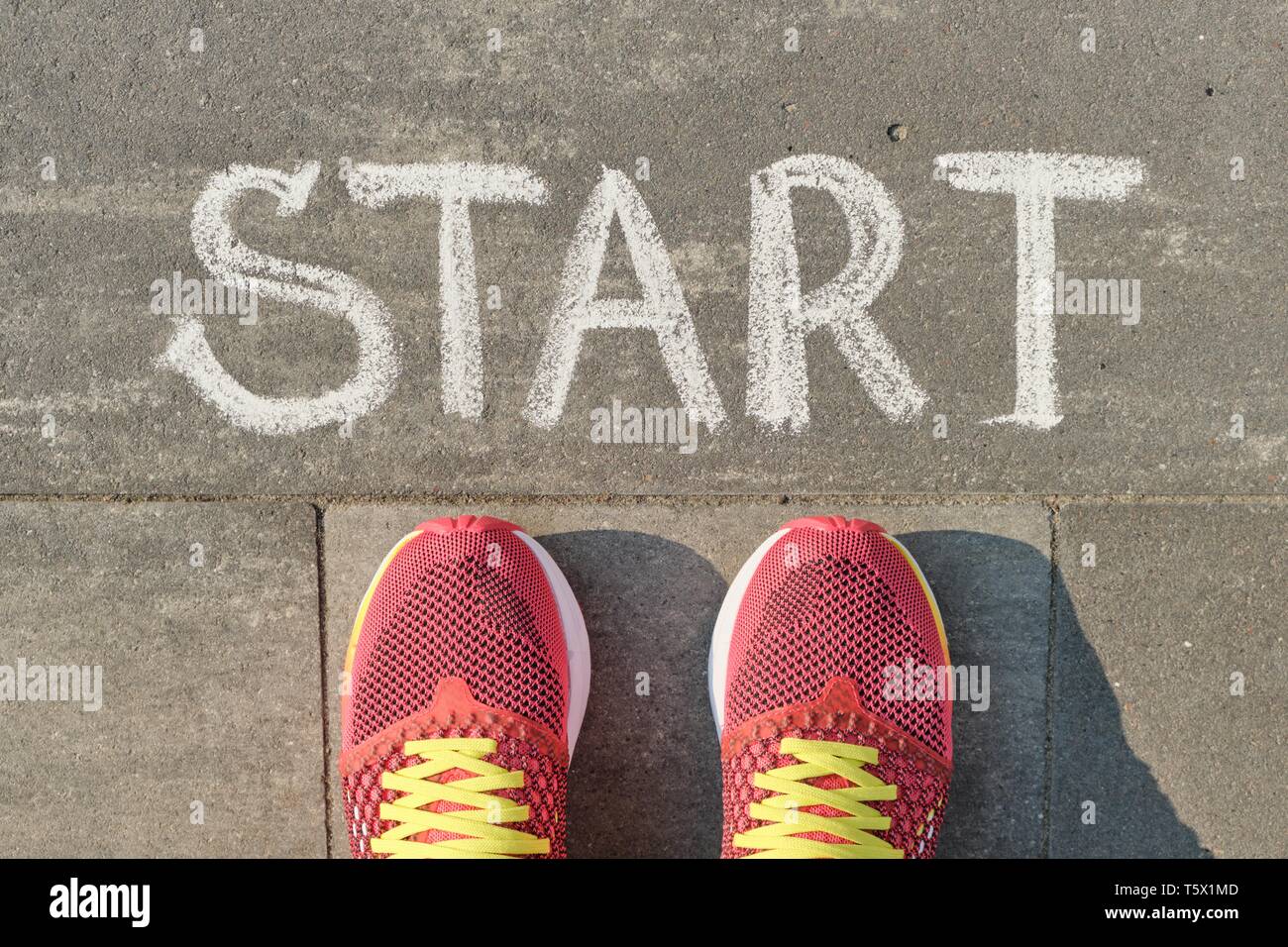 Word start written on gray pavement with woman legs in sneakers, view ...