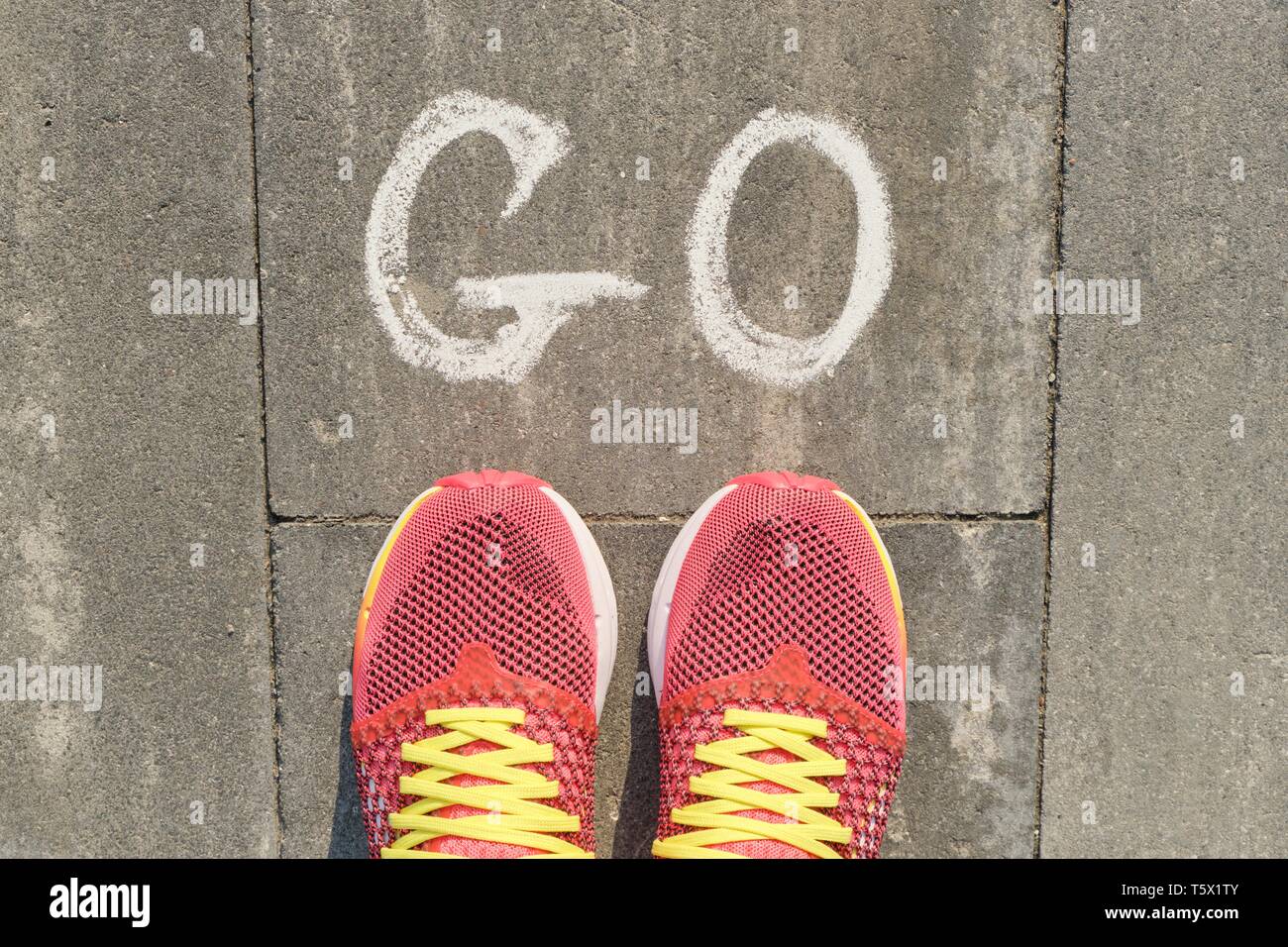 Word go written on gray sidewalk with women legs in sneakers, top view ...