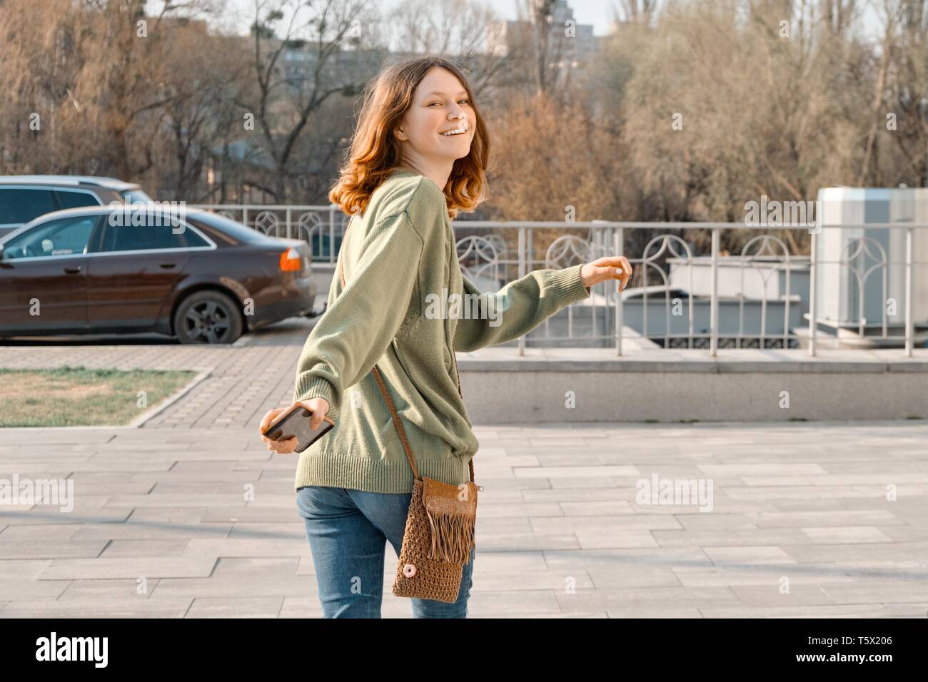Walking young smiling girl teenager looking in camera through back with ...