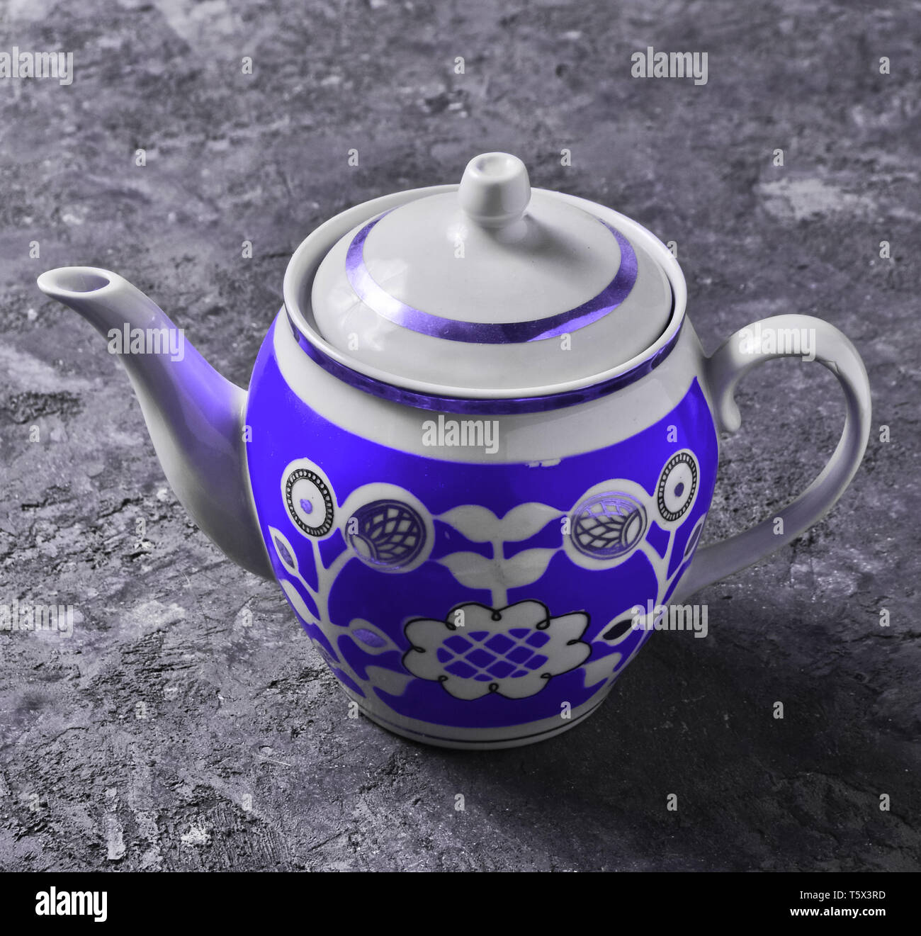 An antique ceramic teapot close-up with patterns on a black concrete ...