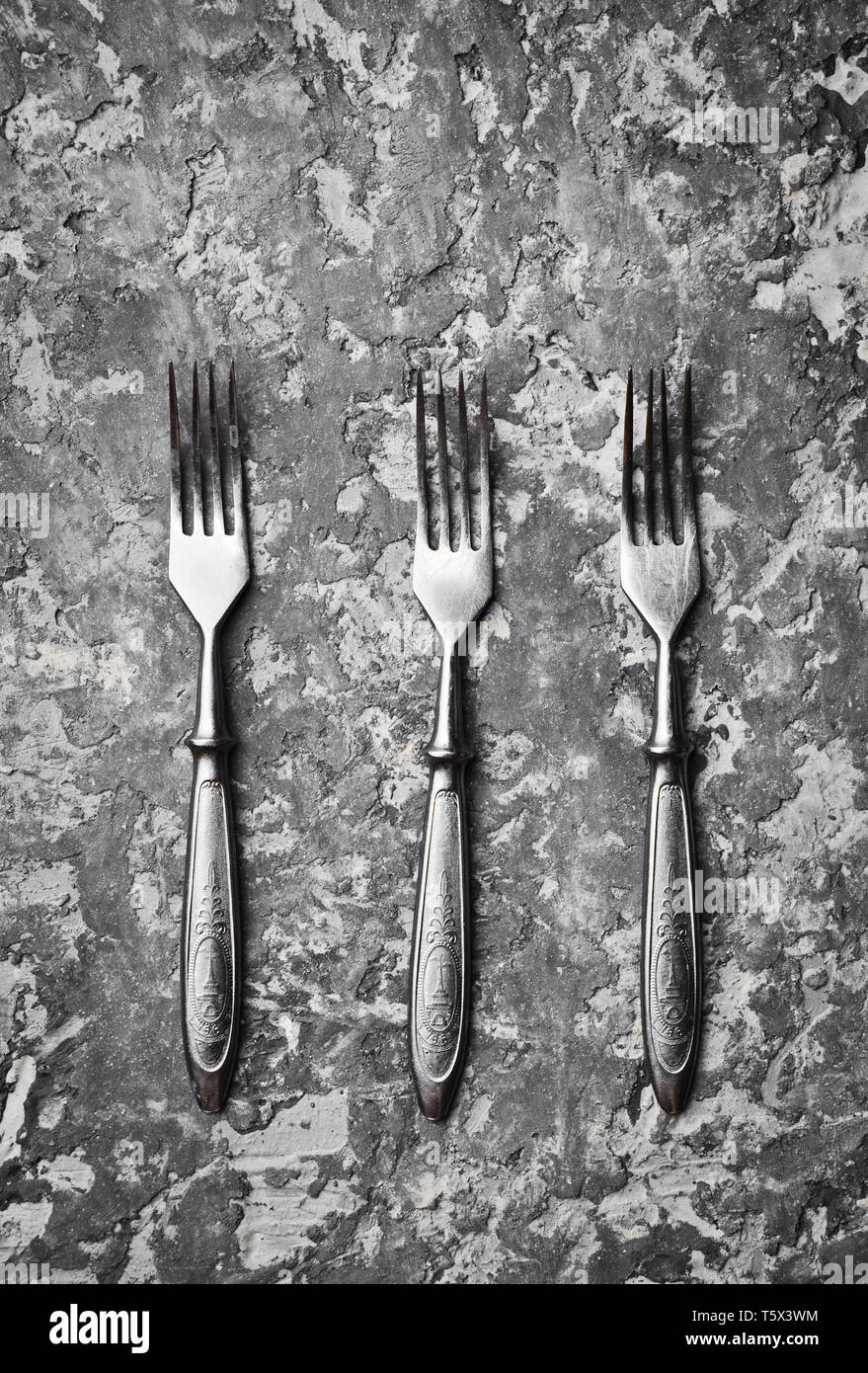 Three antique forks on a gray concrete table. Top view Stock Photo - Alamy
