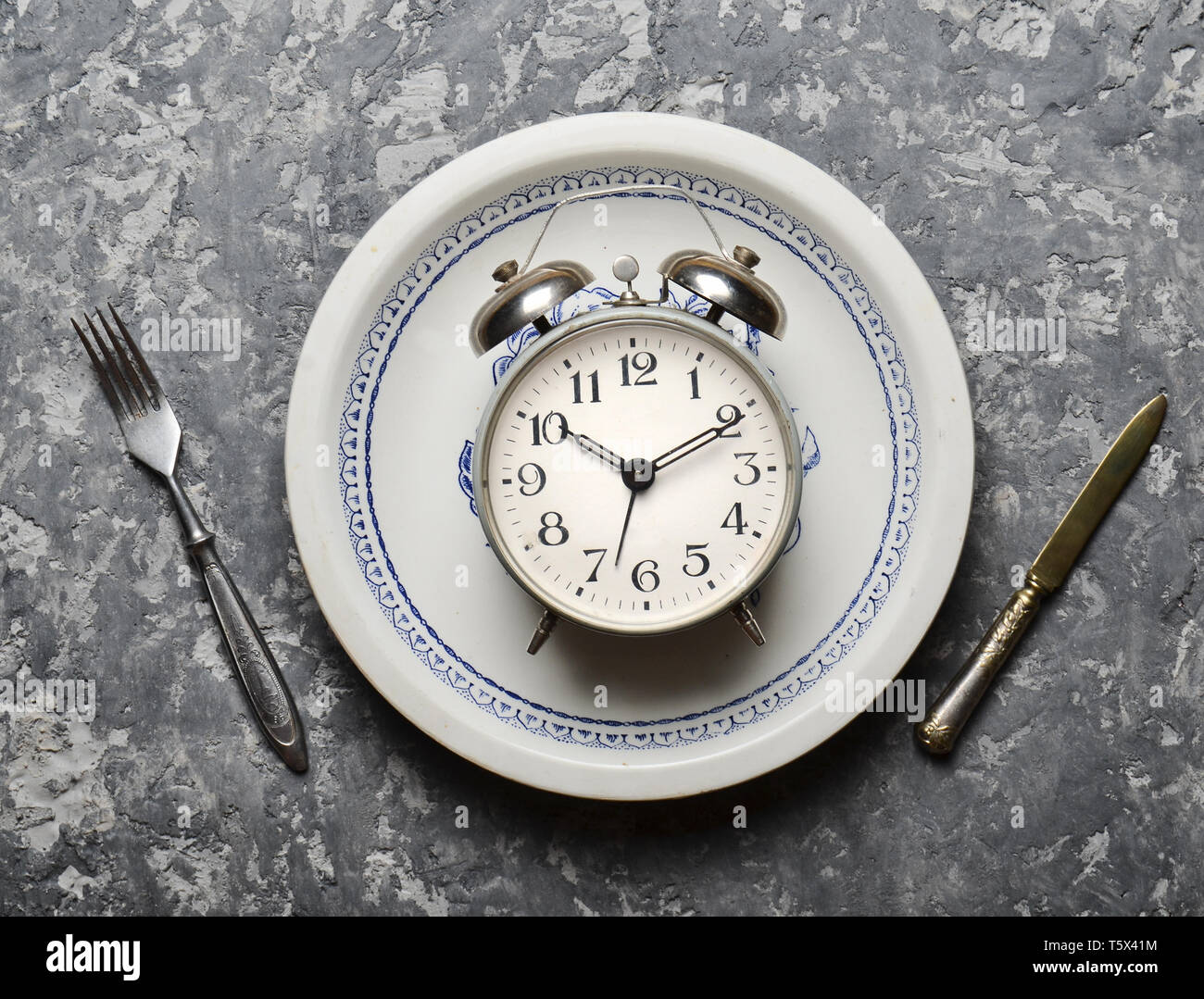 Time for breakfast. Alarm clock in a plate, fork and knife on a ...