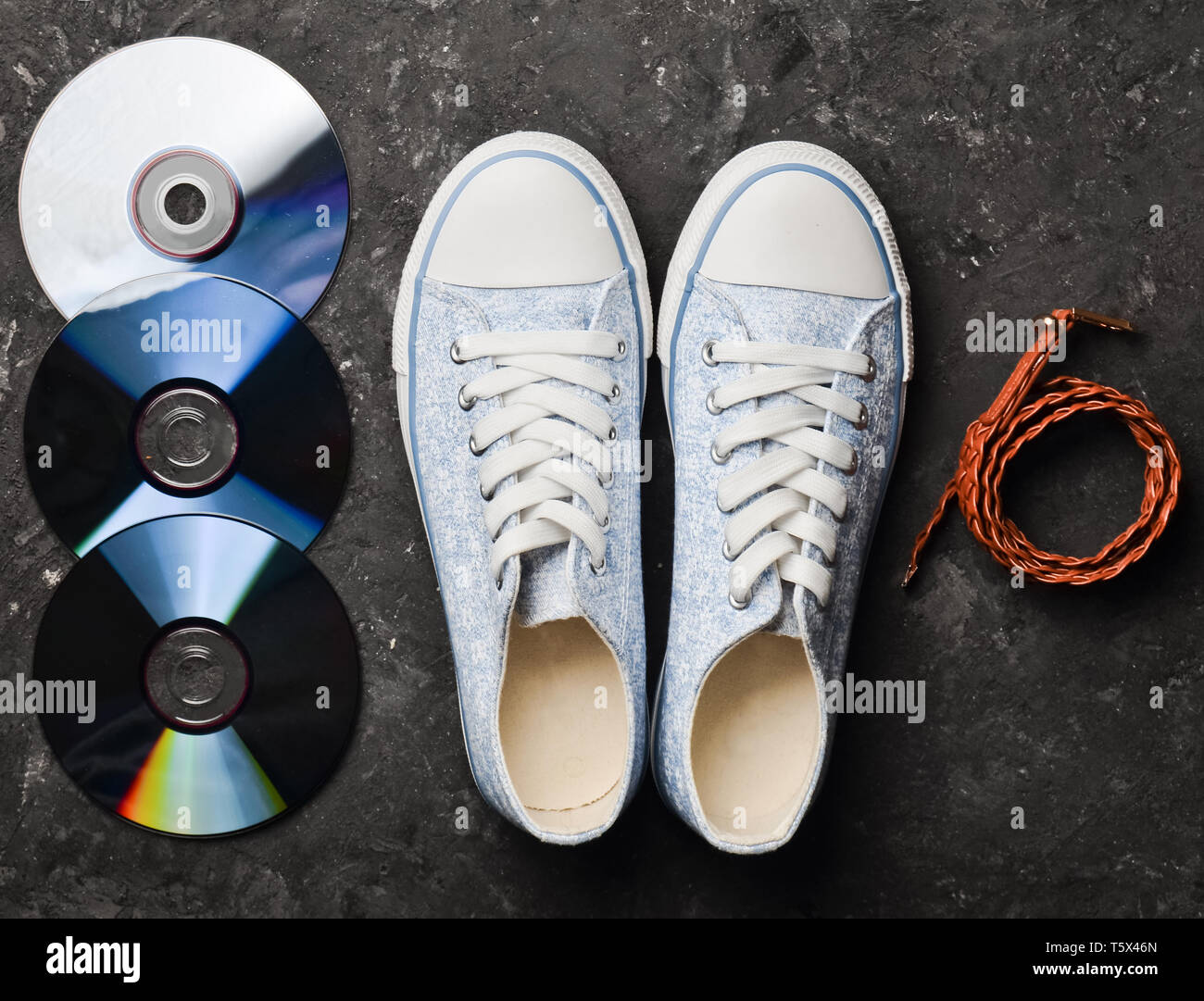 CD, leather strap, stylish retro sneakers from 80s on a black concrete ...