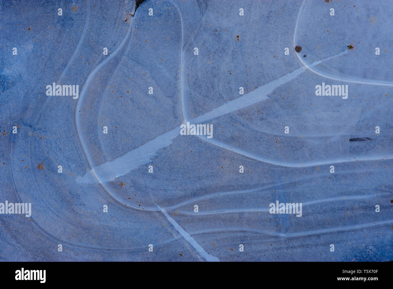 Detail of a frozen puddle captured on a frosty winter morning reveals ...