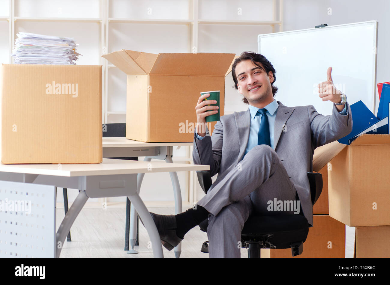 Young man employee with boxes in the office Stock Photo - Alamy