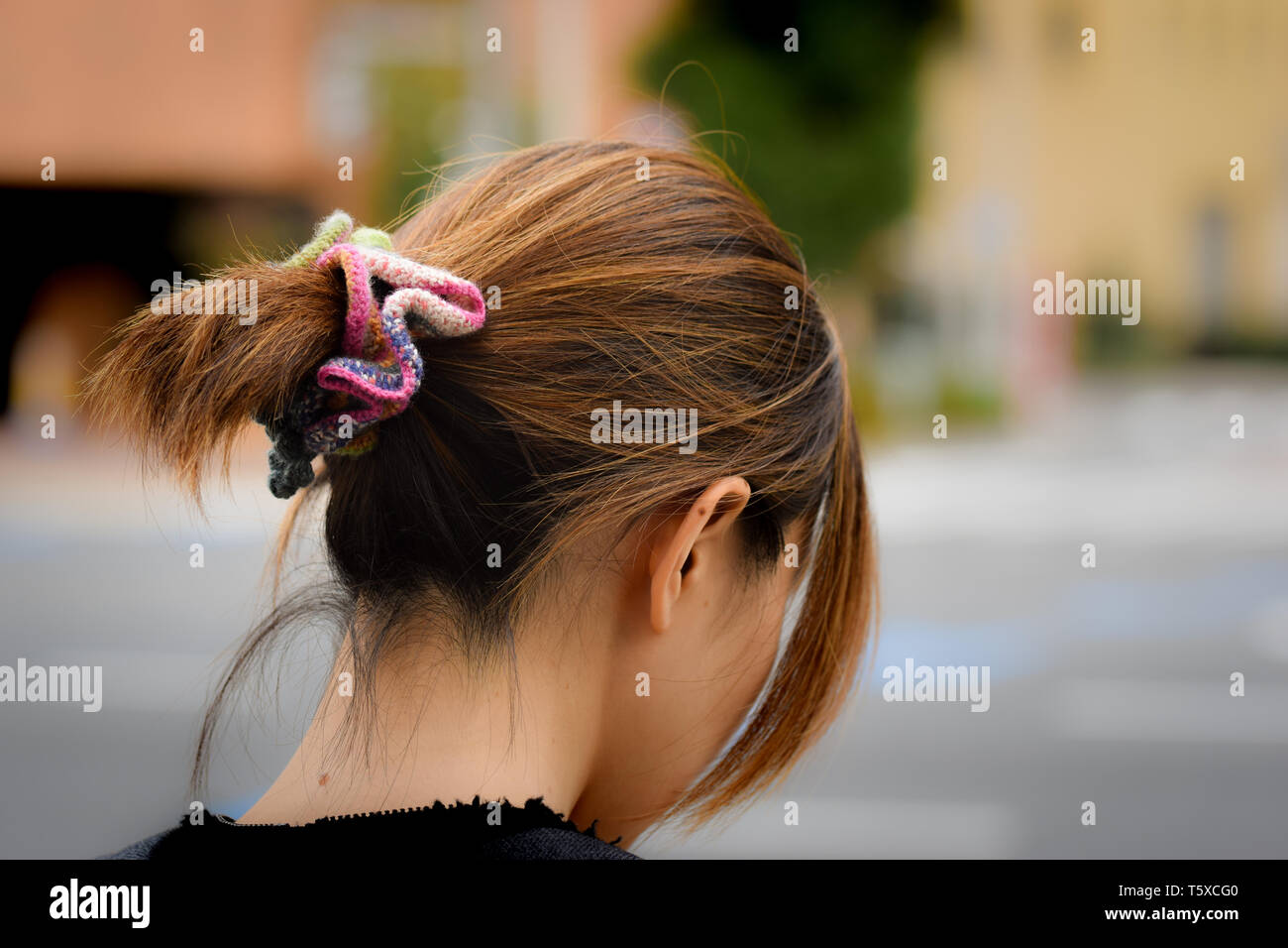 A brunette Japanses woman looks down and away, wearing a colourful ...