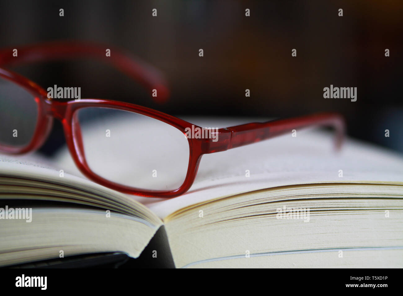 View on pages of open book with red reading glasses Stock Photo - Alamy