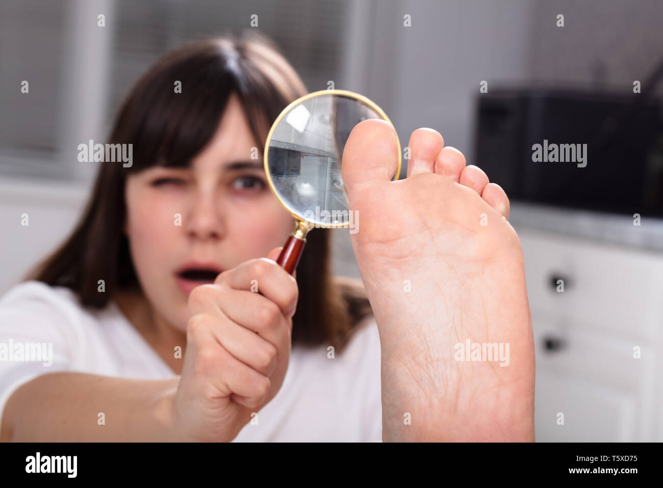 Shocked Young Woman Looking At Her Toe Nails With Magnifying Glass ...