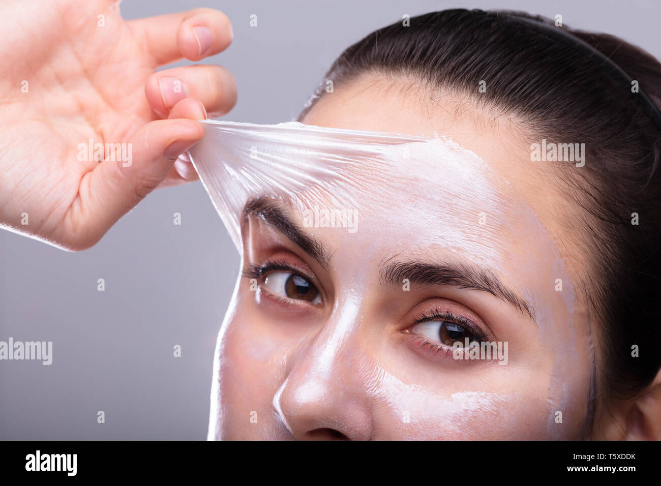 Portrait Of A Beautiful Young Woman Removing Peeling Mask From Her Face ...