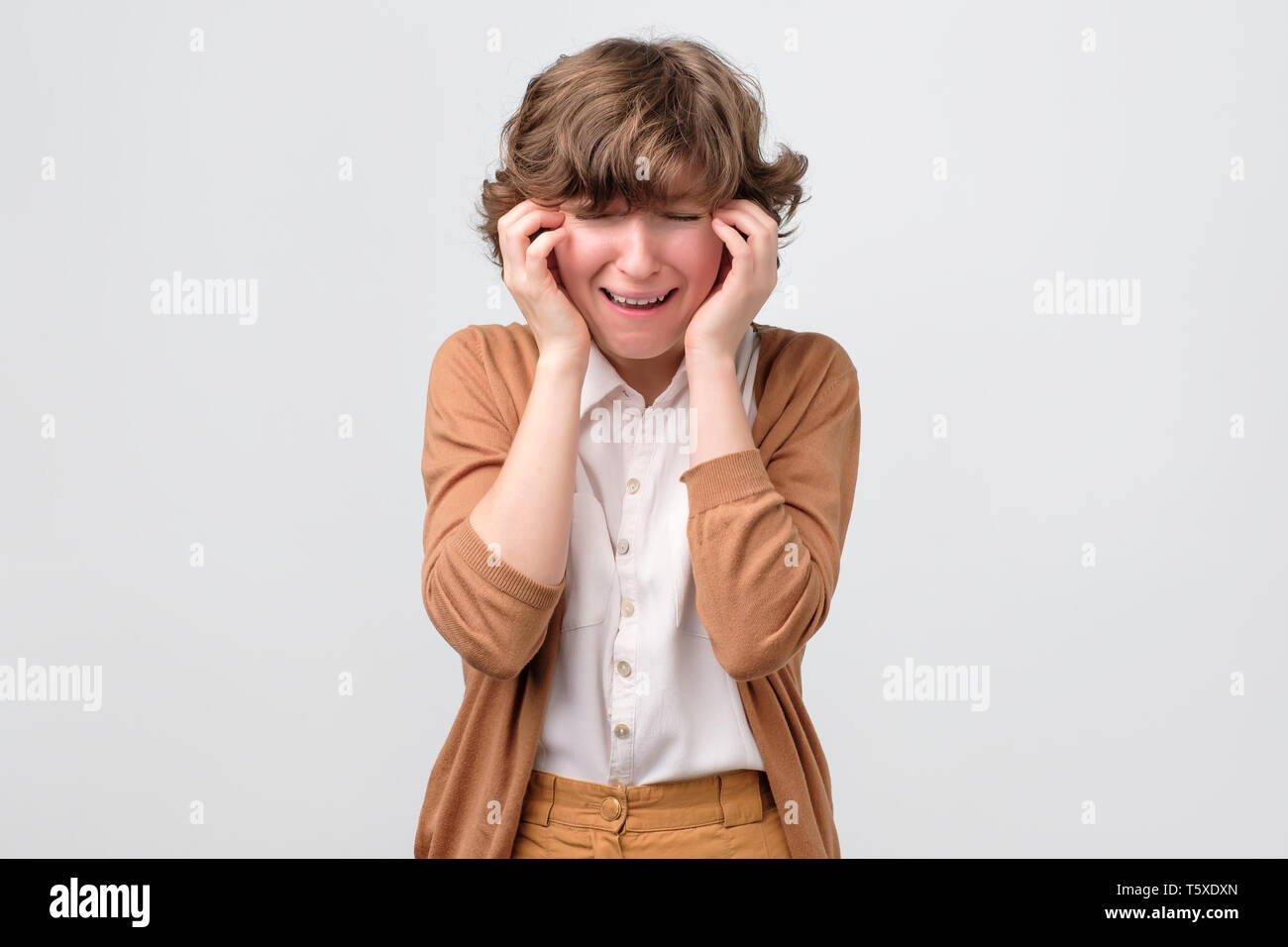 Displeased crying young woman putting hand on head isolated on gray ...