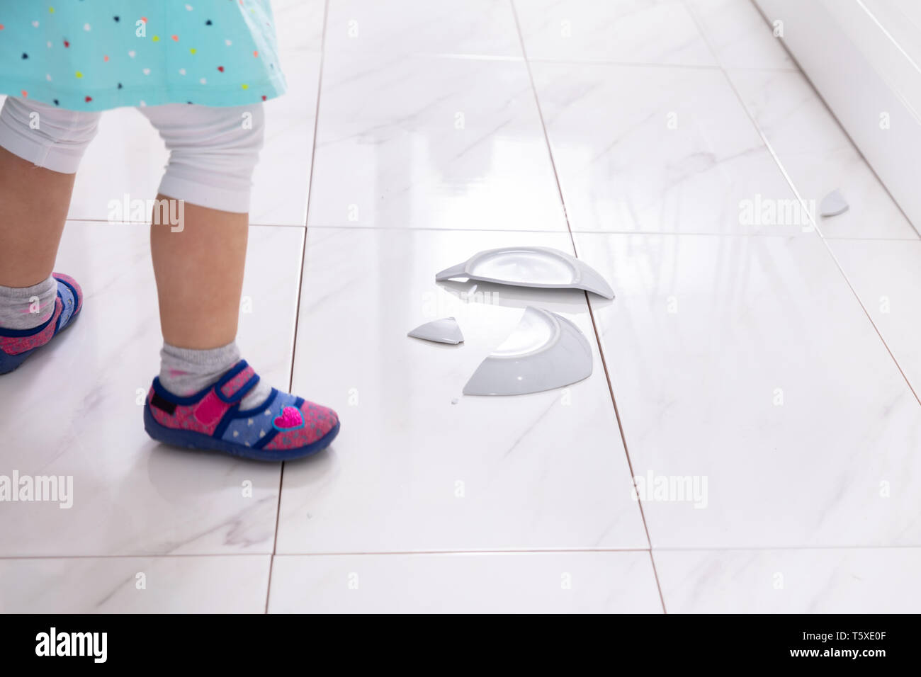 Little Girl Looking At Broken White Plate In Kitchen Stock Photo - Alamy