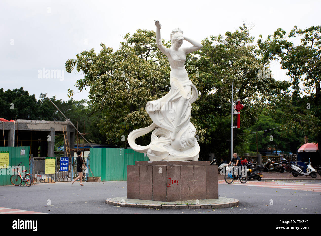 Chinese people walking crossing traffic road with sculpture angel woman ...