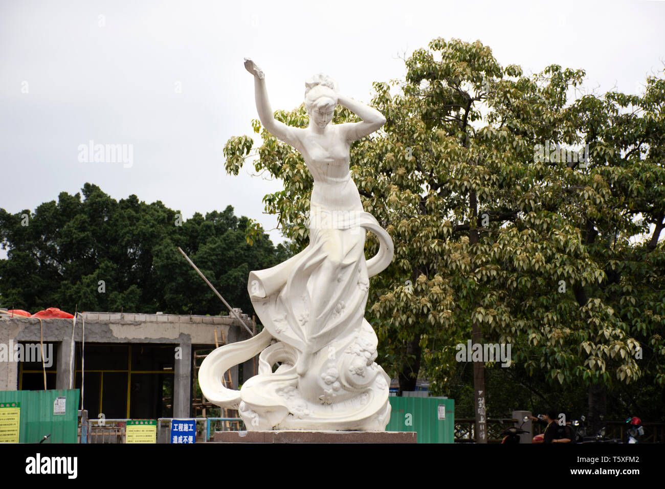 Chinese people walking crossing traffic road with sculpture angel woman ...