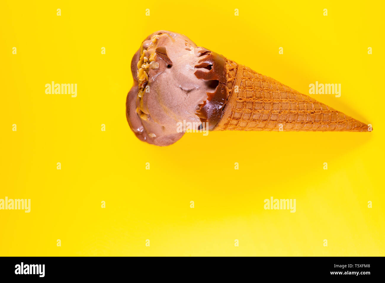 top view chocolate flavor ice cream cone in a melting process on yellow ...