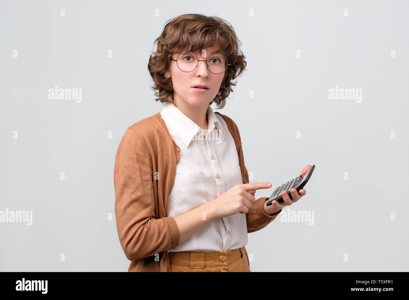 Troubled cute young woman counting her money, frowning troubled ...