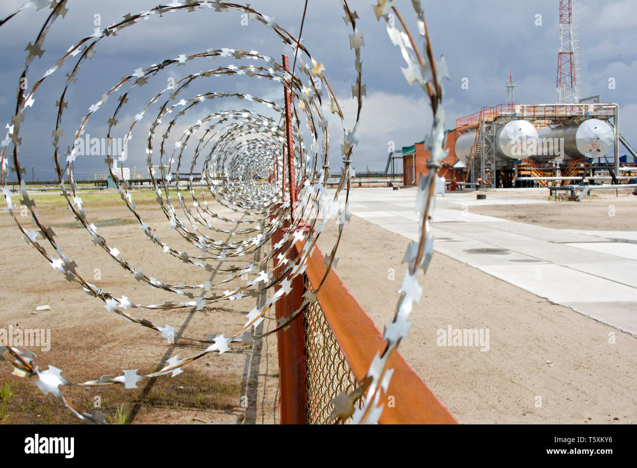 Barbed wire around oil refinery center Stock Photo - Alamy