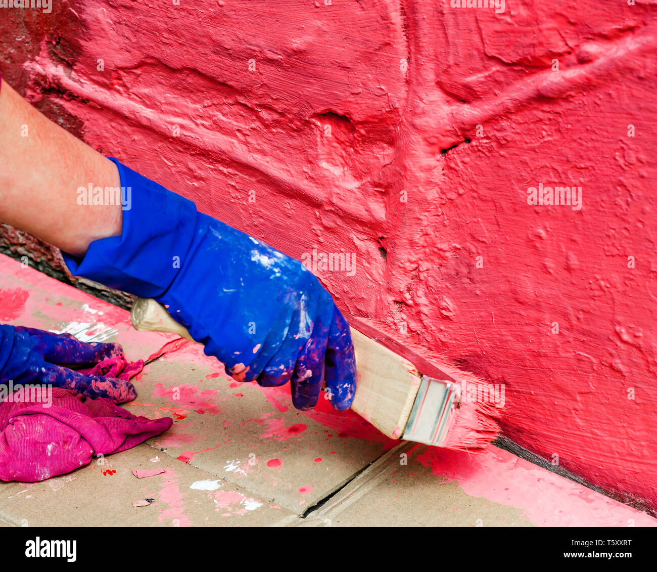 Paint the wall in red with a large wide paint brush Stock Photo - Alamy