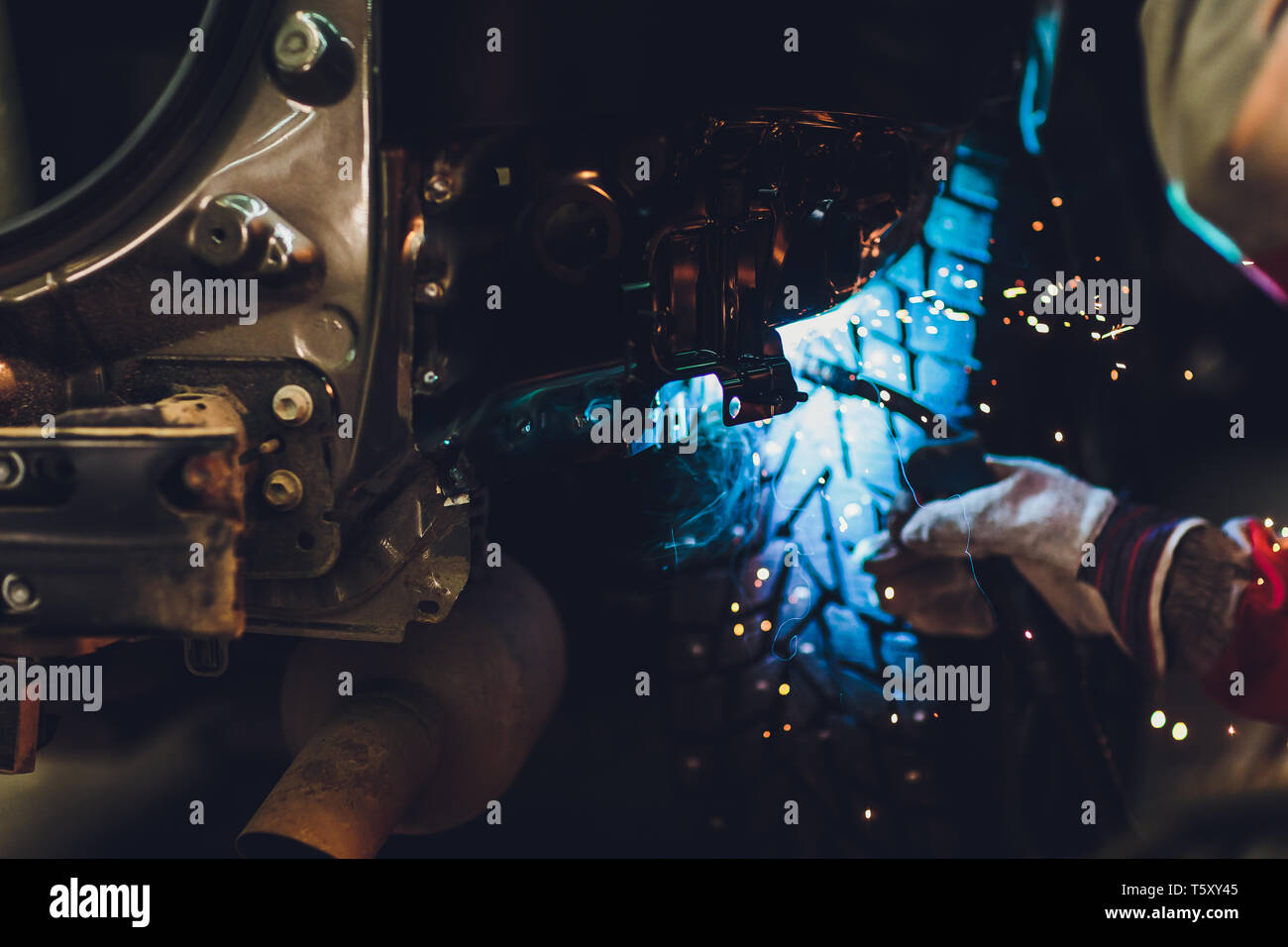 professional repairman worker in automotive industry welding metal body ...