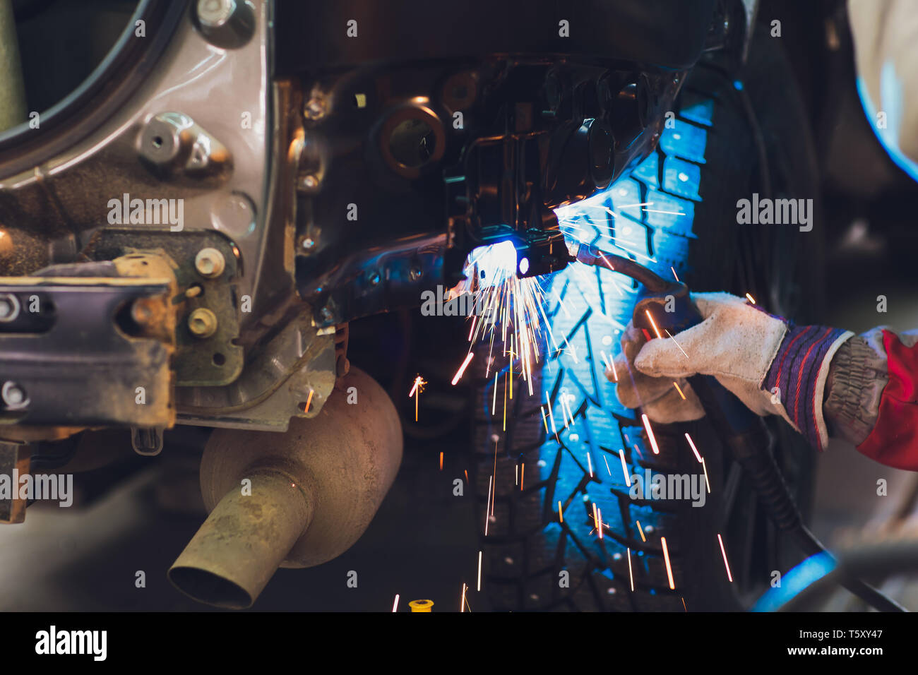 professional repairman worker in automotive industry welding metal body ...