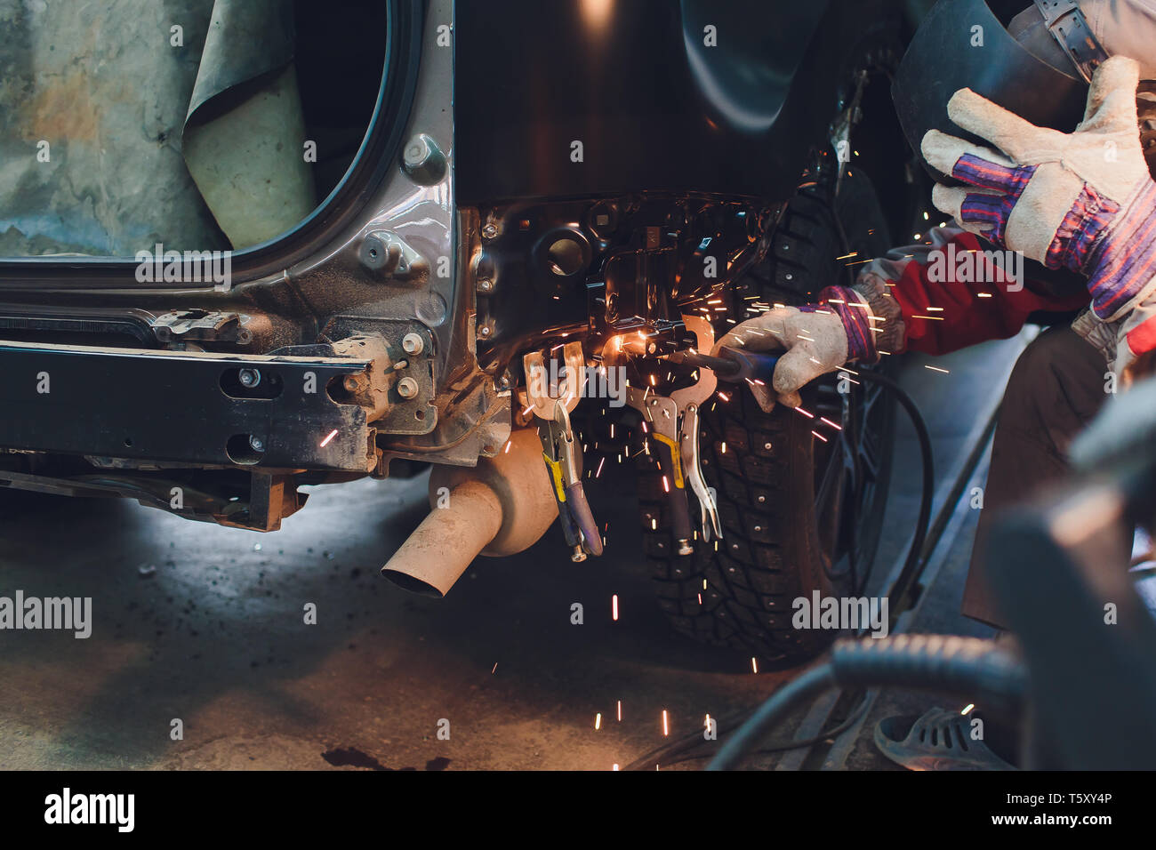 professional repairman worker in automotive industry welding metal body ...