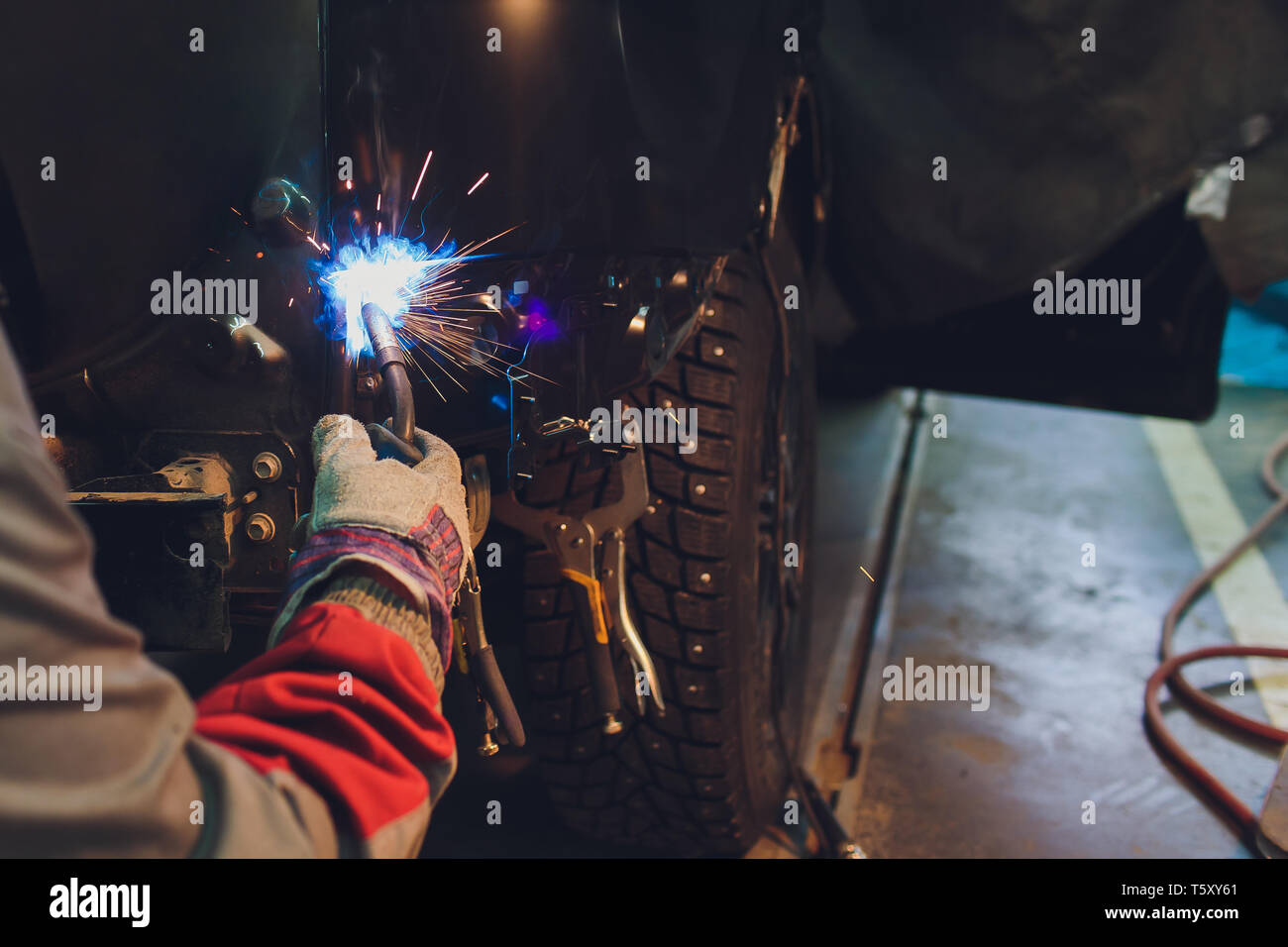 professional repairman worker in automotive industry welding metal body ...