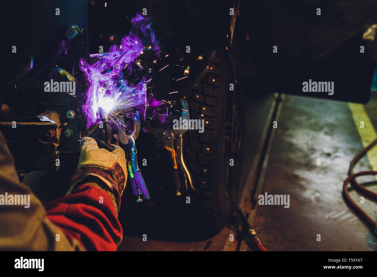 professional repairman worker in automotive industry welding metal body ...