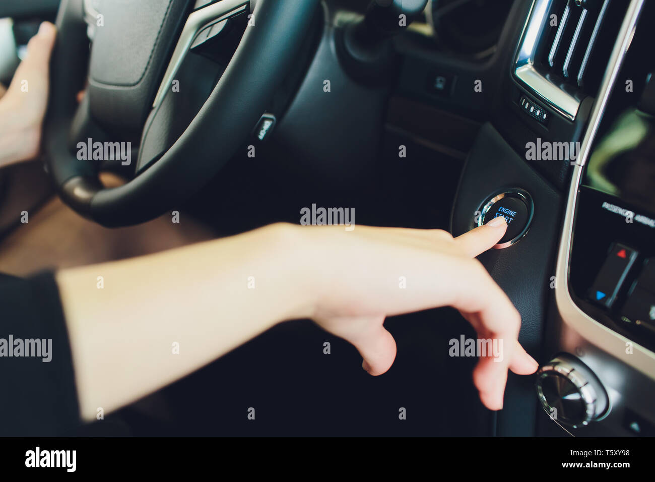 Woman starts the car engine with start-stop button. Modern car interior ...