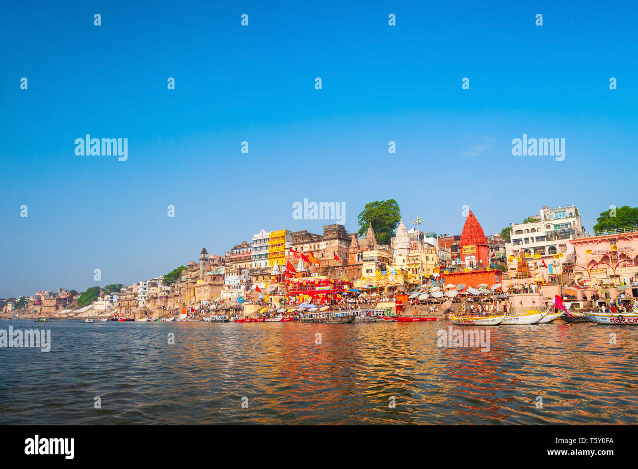 VARANASI, INDIA - APRIL 12, 2012: Colorful boats and Ganges river bank ...
