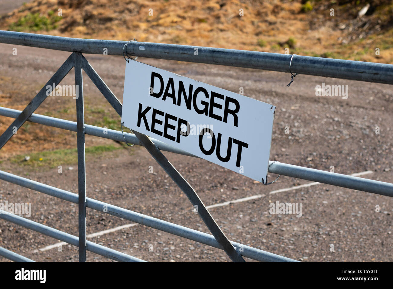Danger keep out sign on metal gate boundary to disused contaminated ...