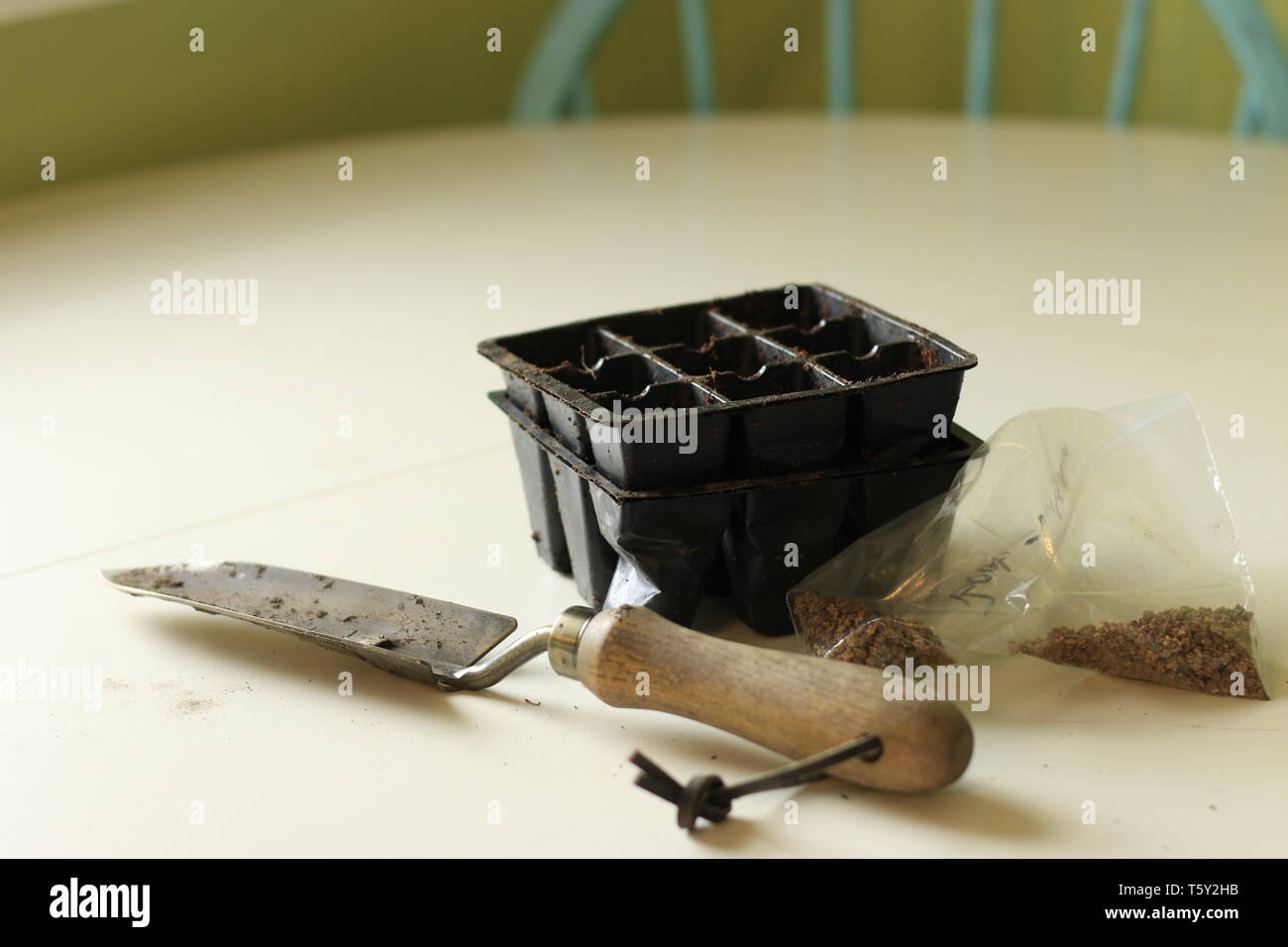 A bag of seeds next to a small shovel and modules for seed starting ...