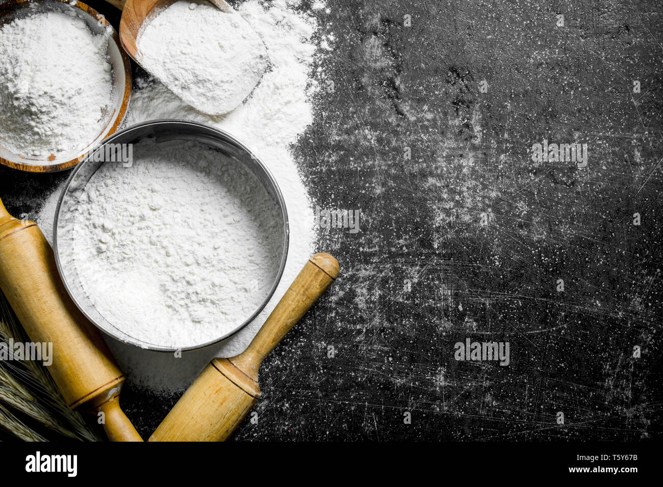 Flour in a sieve and bowl. On dark rustic background Stock Photo - Alamy