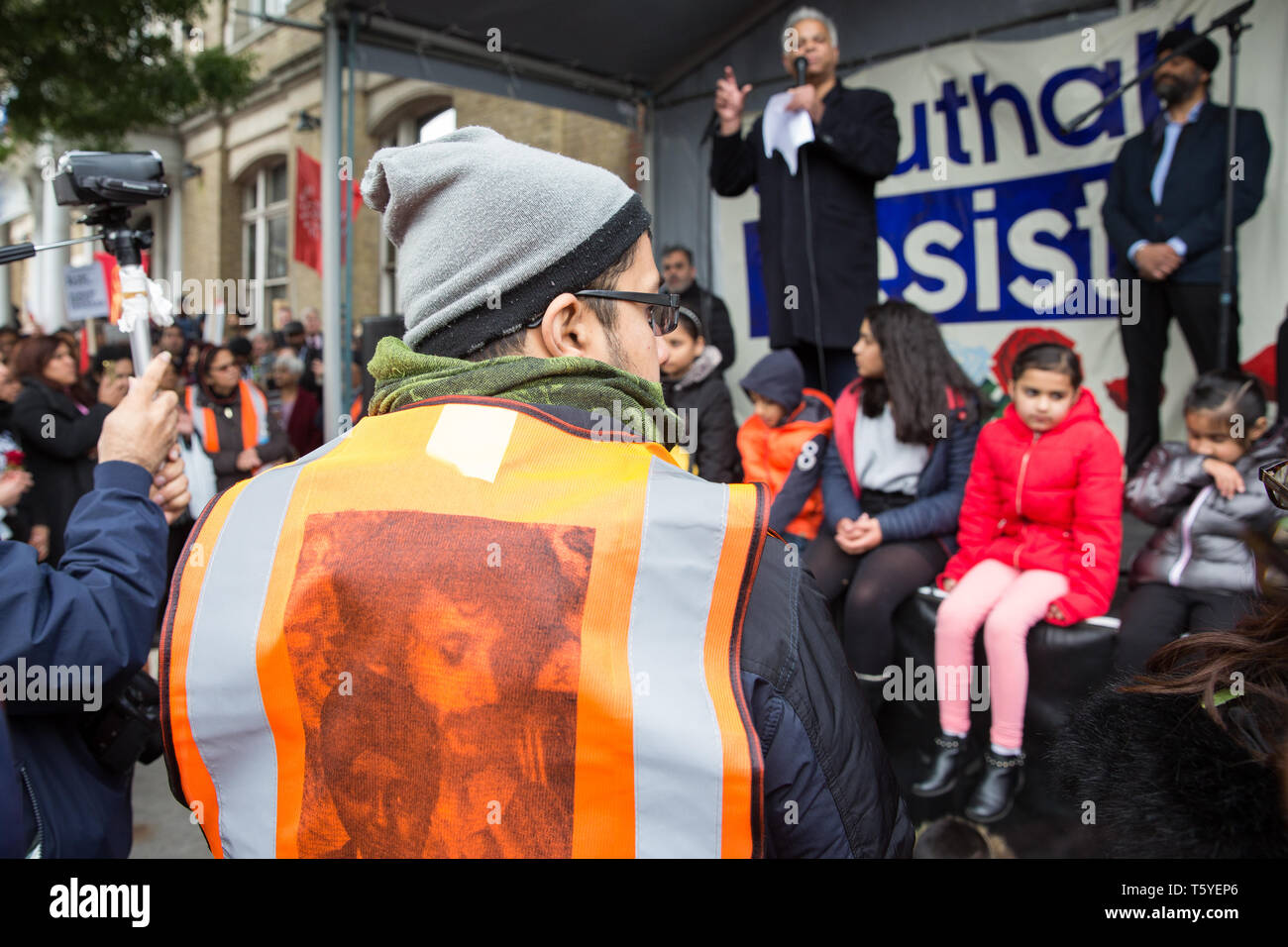 Southall, UK. 27th April 2019. A steward wearing a vest bearing the ...