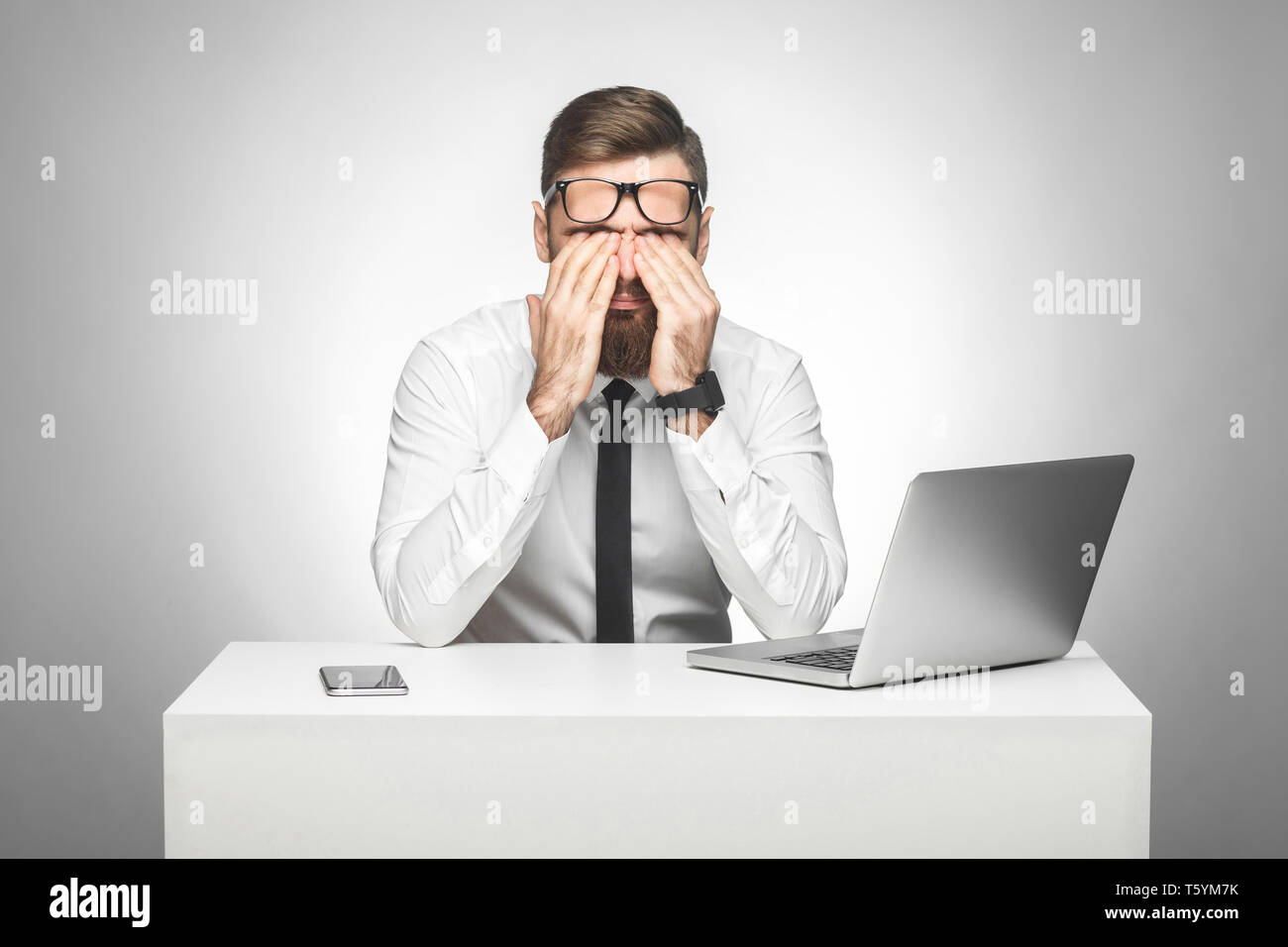 Madly tired young manager in white shirt and black tie are sitting in ...